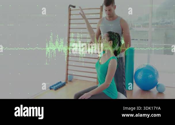 Trainer tapping client's shoulder and guiding arm lift on ball for ...