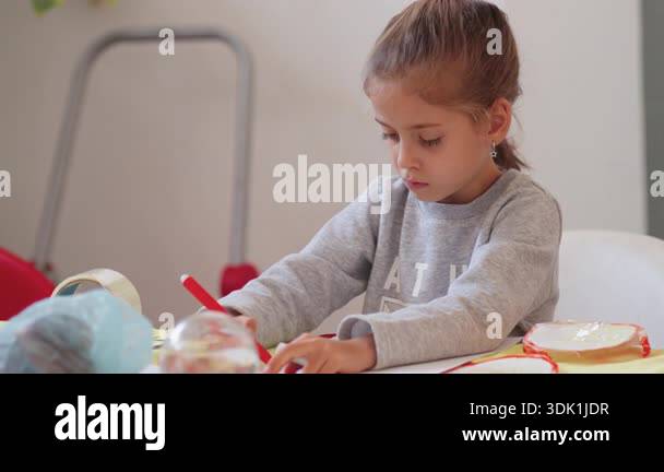 Focused young girl drawing line with red felt tip pen and carefully ...