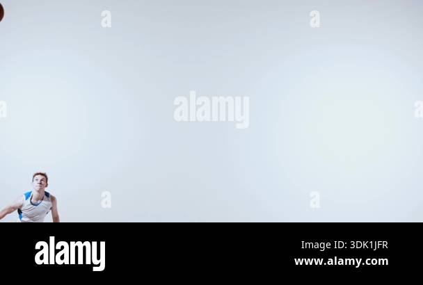 Basketball player extending arm sideways holding ball in wide athletic ...