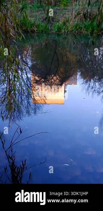 Perfect reflection of light building and trees on still water, bathed ...