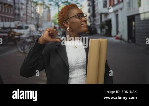Energetic african american woman holds rolls of blueprints and points ...