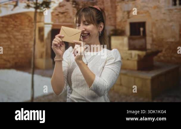 Woman holds kraft envelope to face with closed eyes and smile in old ...