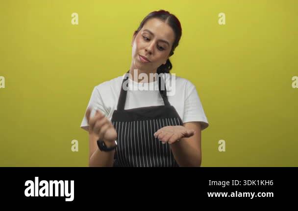 Young brunette woman in striped apron rubs palm and pinches fingers ...