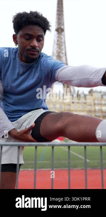Focused african american athlete warming up his hamstring and leg ...