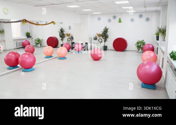 Spacious white fitness studio featuring scattered red and pink exercise ...