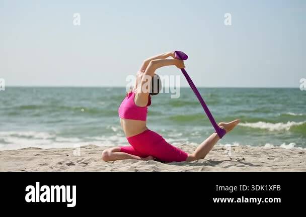 Athletic young woman in bright pink sportswear stretching and ...