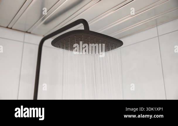 Close-up view of matte black showerhead releasing fine streams of water ...