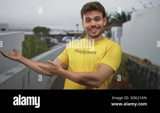 Man posing with hands on hips, wearing yellow tshirt printed happiness ...
