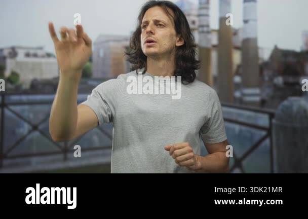 Man with long hair reaching out hand on old town street by stone ...