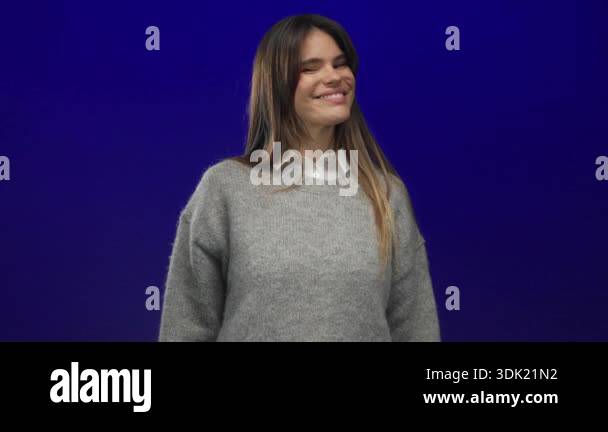 Woman giving thumbs up with a cheerful smile against a vibrant blue ...