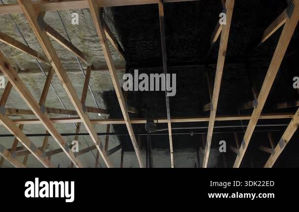 Wooden ceiling beams being spray painted black over foam insulation ...