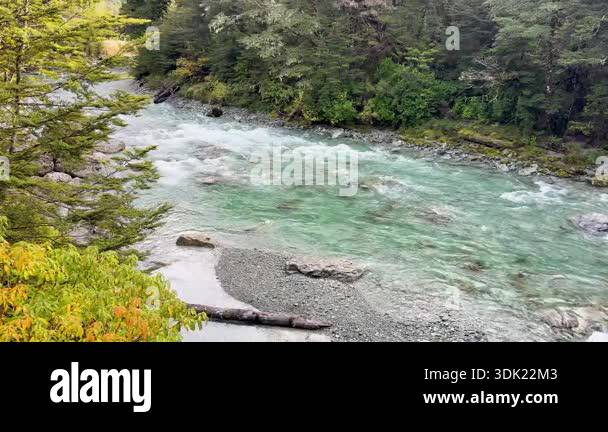 Clear turquoise river from glacial melt flows rapidly past rocks and ...