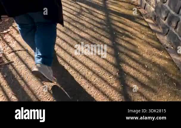 Person walking along a sunlit path Stock Video Footage - Alamy
