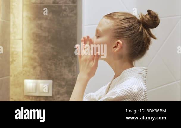 Teen Girl Moisturizing Face With Toner in Bathroom, Wearing Bathrobe ...