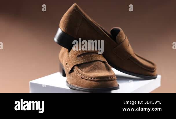 Pair of stylish brown shoes on podium against color background ...