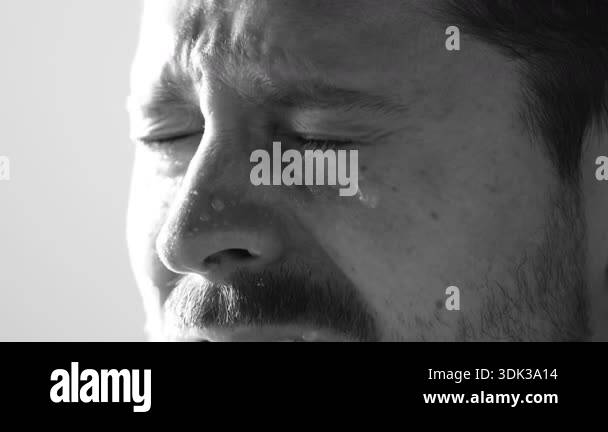 Sad man crying on light background, closeup. Black and white effect ...