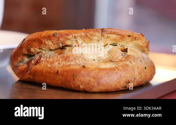 A baker prepares a loaf of bread at a bakery in the afternoon light ...