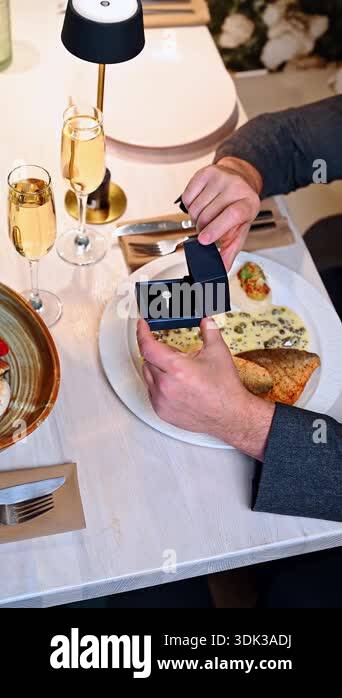 Couple shares meal while one partner proposes with an engagement ring ...