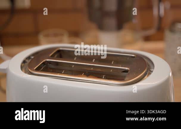 Two toasts jump out of the toaster and are picked up by hands, close-up ...