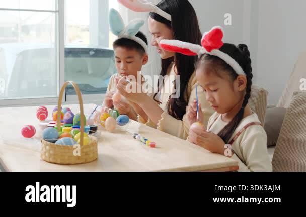 Easter happiness. A mother and kids enjoy painting Easter eggs together ...