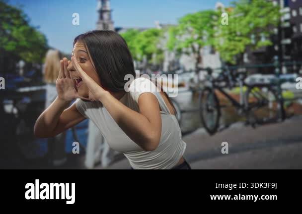 Young hispanic woman with hands cupped around mouth shouting on a ...