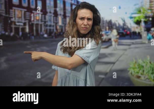 Woman in blue dress pointing finger forward with stern expression on ...