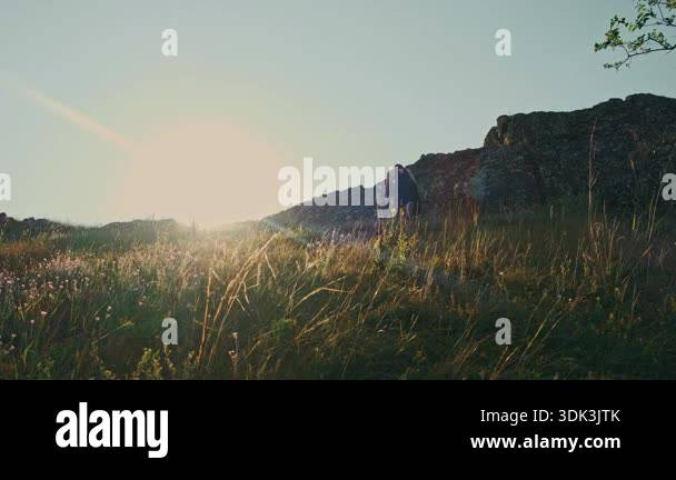Sunlit Meadow With Lone Hiker, Backlit Figure Standing Near Rocky ...