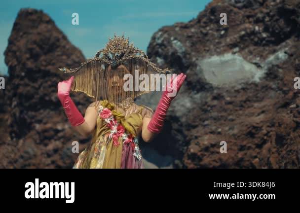 A surreal artistic shot of a woman standing alone in a dark lava field ...