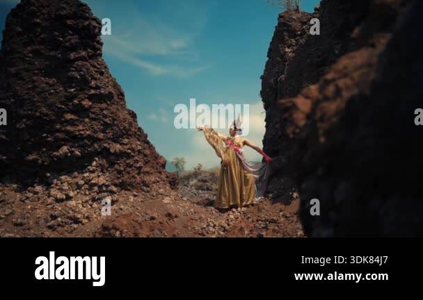 A dramatic wide shot of a woman in a gold dress and halo crown striking ...