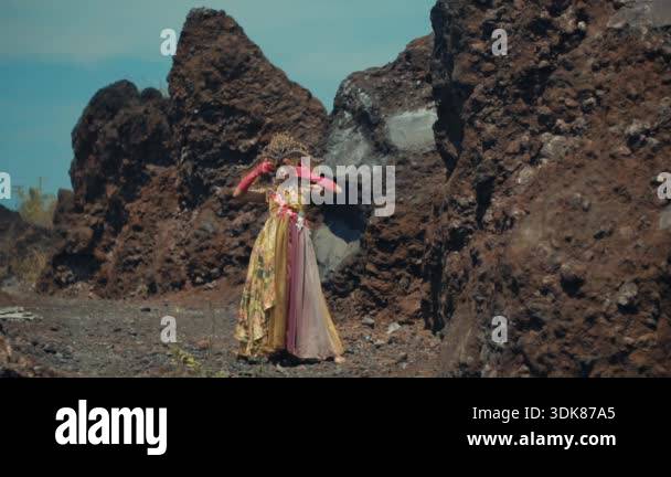 A mysterious dancer wearing a unique gold fringe headpiece and colorful ...