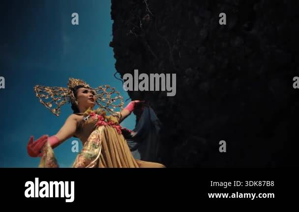 Camera tilts up from the ground to reveal a majestic woman in a gold ...