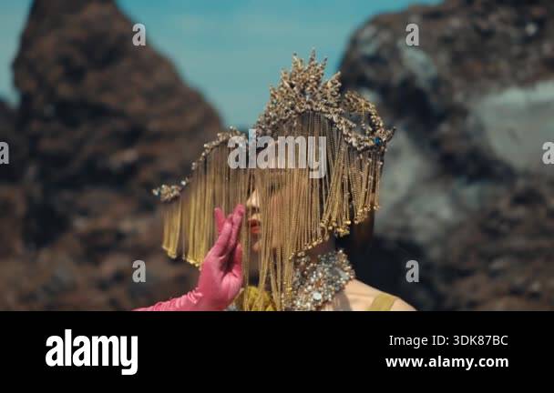 A powerful stance by a female model wearing a face-covering gold mask ...