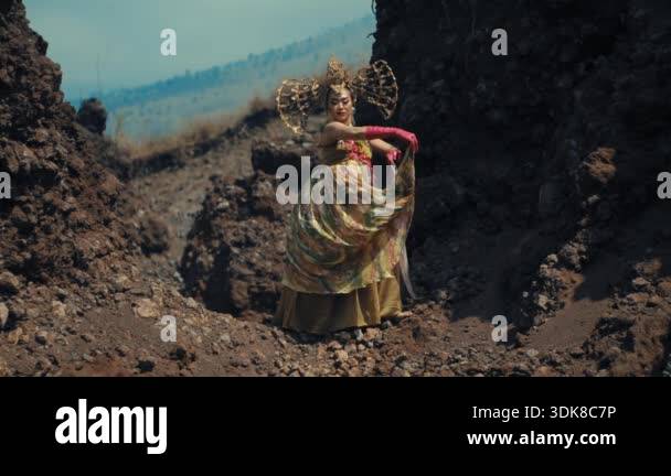 Wide shot of a woman in a gold dress and crown waving a sheer multi ...