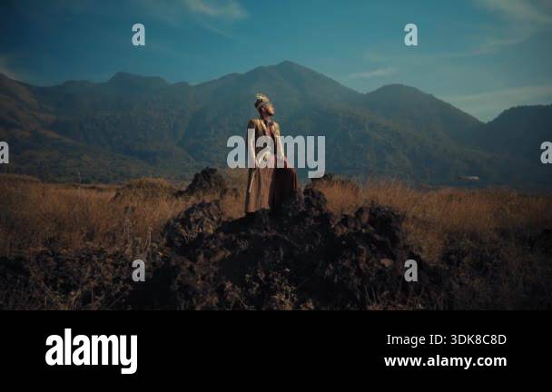 Wide shot of a man in traditional Javanese gold clothing standing ...