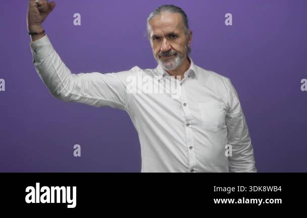 Man flexes bicep and clenches fist in purple studio with long hair and ...