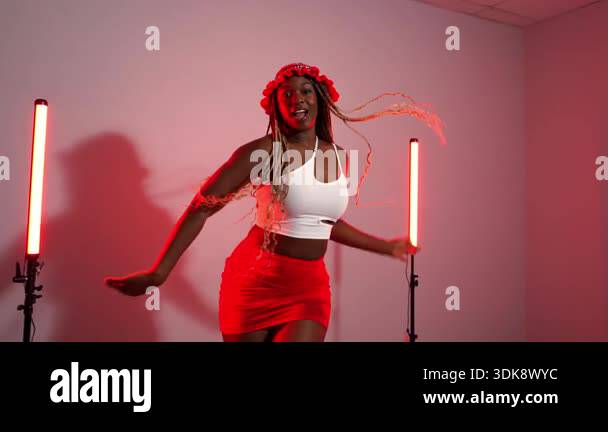 Stylish young woman with long braids performing an energetic afrodance ...