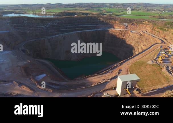 Open pit quarry mining with heavy machinery working around deep ...