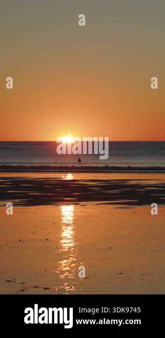 Timelapse of Warm sunset colors reflect on wet sand as Pacific Ocean ...