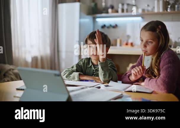 Pupil boy answering online lesson studying remotely with sister home ...