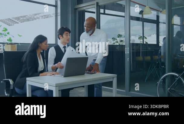 office team reviewing printout when senior colleague leaning over ...