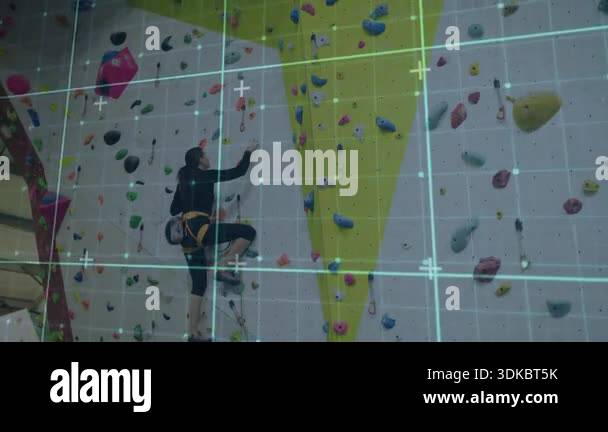 Placing left foot on lower hold, climber ascending fitness wall ...