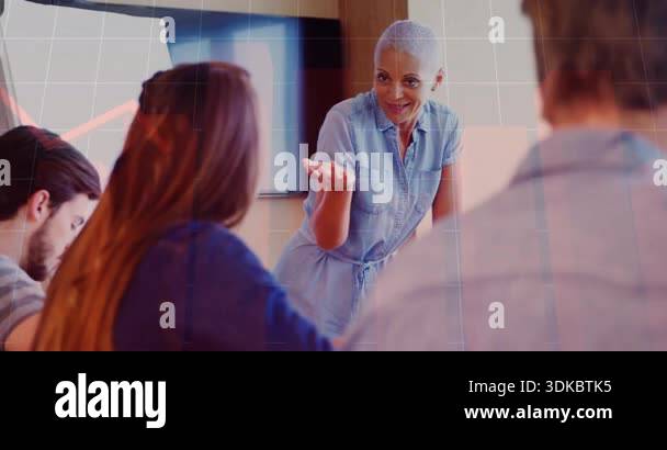 Mature presenter greeting colleagues and pointing at red business graph ...