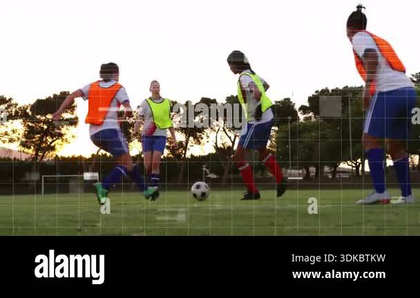 Four female players chasing rolling ball in soccer drill executing ...
