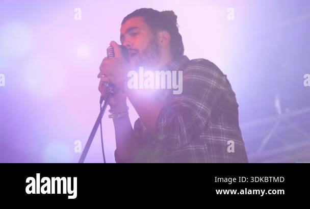 Singer holding mic concert stage activating purple pink lens flares ...