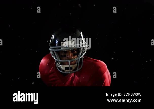 Helmeted football player emerging from dark, scanning and gripping ball ...