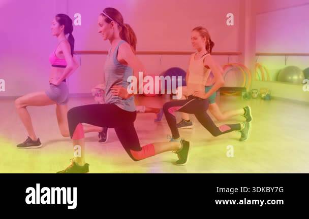 Instructor stepping forward initiating lunges in fitness studio with ...