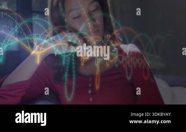 Woman sitting on sofa, responding to health tech waveform graphics ...