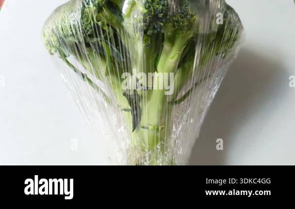 Fresh broccoli wrapped in transparent plastic packaging on a clean ...