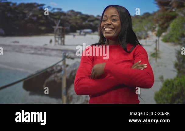 Woman smiling with hands raised near head, red sweater and cropped ...