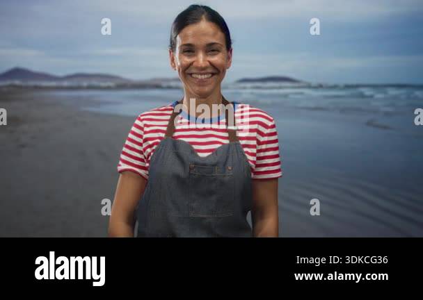 Woman in striped shirt wearing denim apron points fingers to cheeks ...